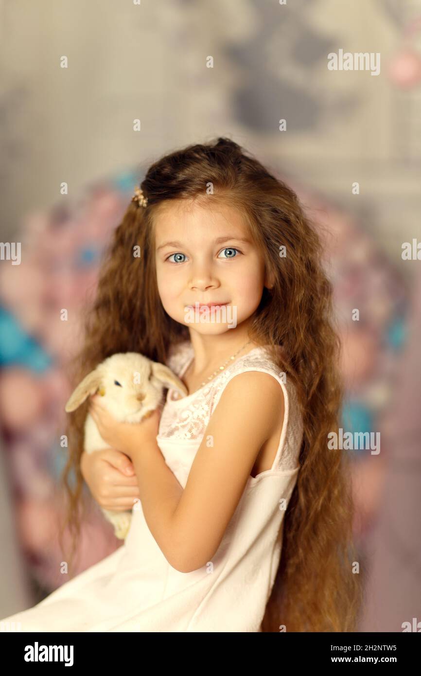 Portrait of cute little princess hold white rabbit in her hands. Studio ...
