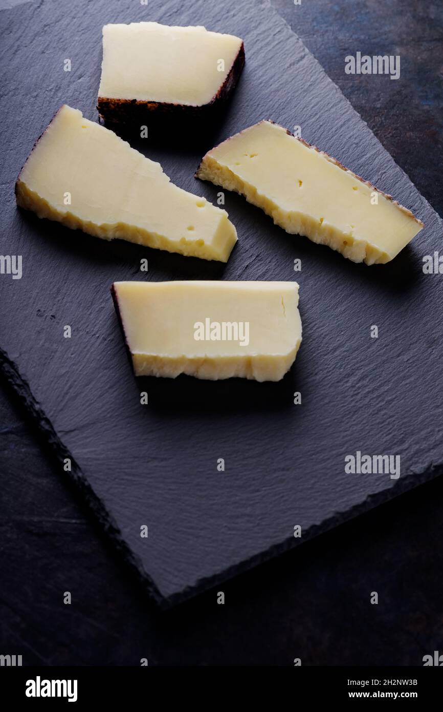 Hard cheese pieces on a dark background. Goat cheese on a slate board ...