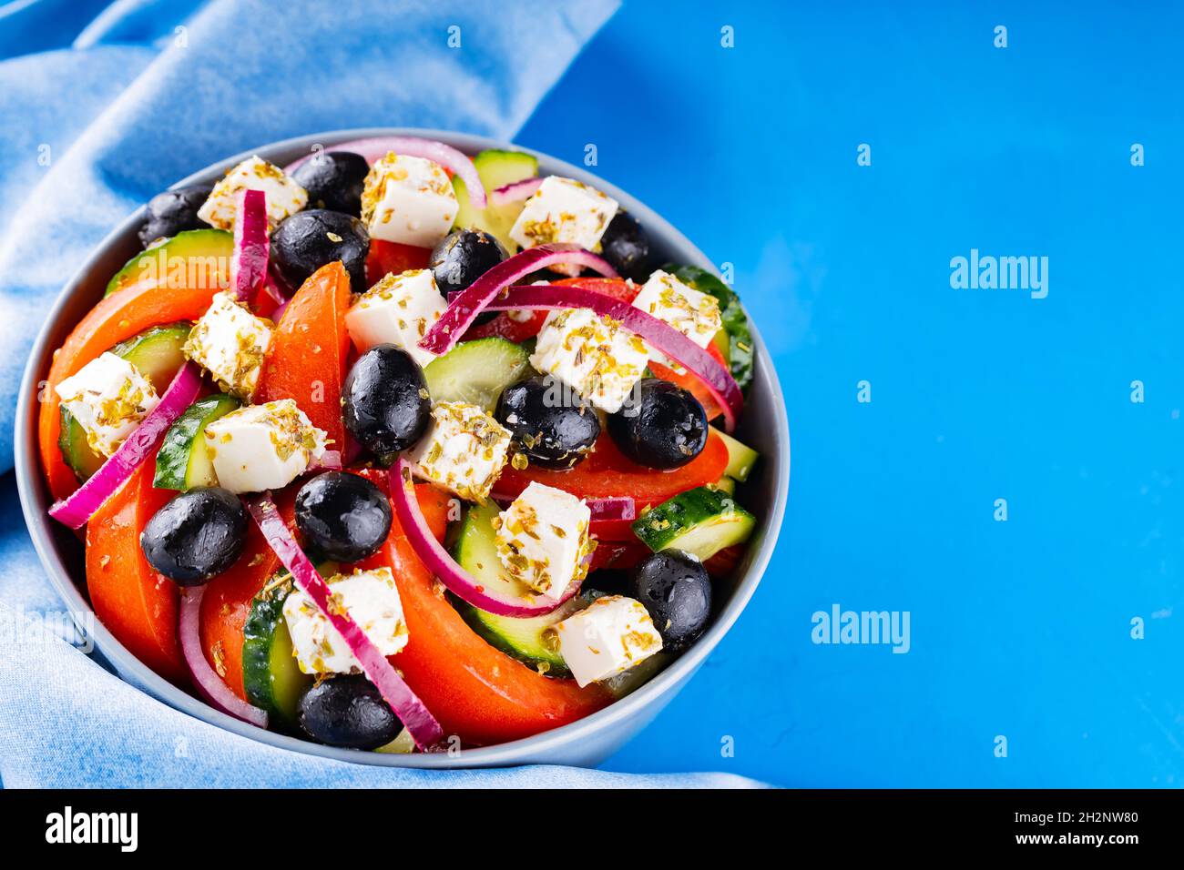 Greek salad and blue napkin on a blue background. Fresh vegetables ...