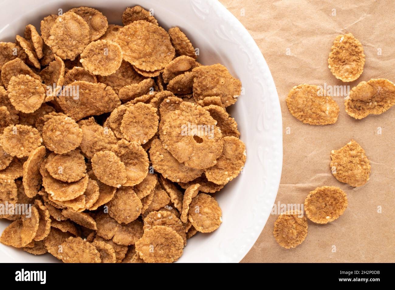 Natural multi-grain flakes in a white ceramic plate on brown paper ...