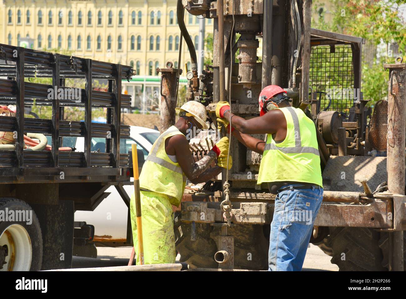 Two African-American construction workers safely drilling hole in city ...