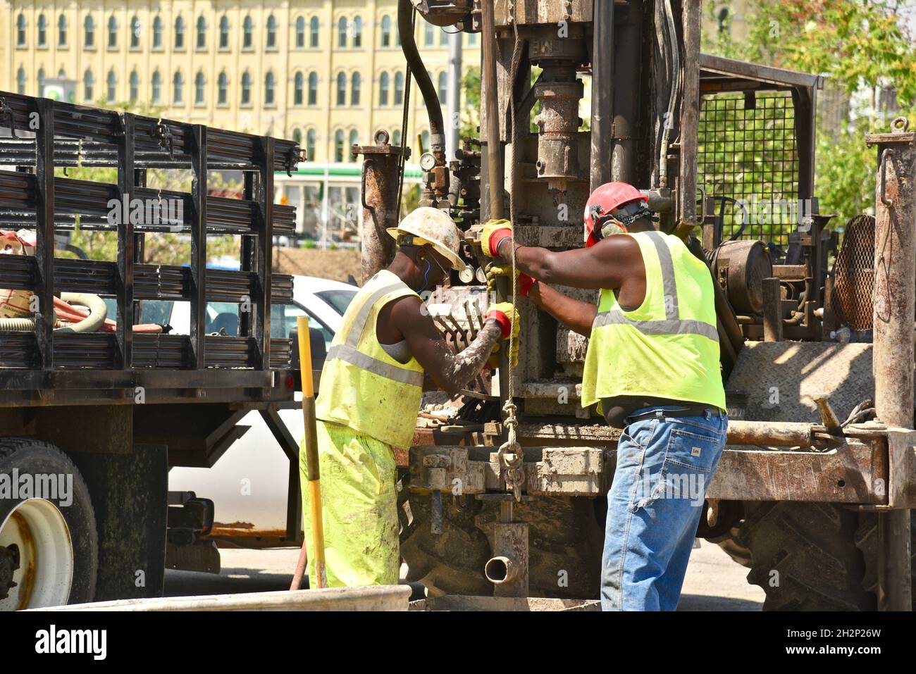 Two African-American construction workers safely drilling hole in city ...