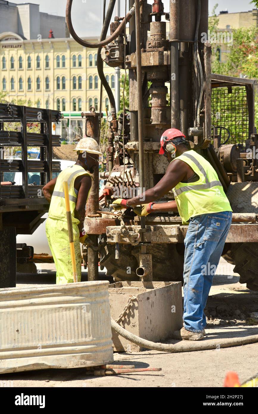 Two African-American construction workers safely drilling hole in city ...