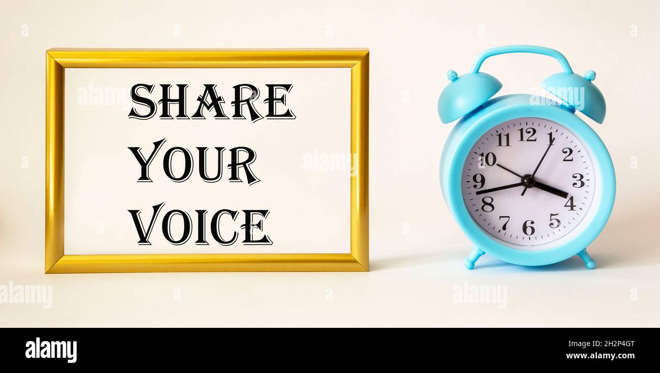 Share your voice written on gold photo frame next to alarm clock on ...