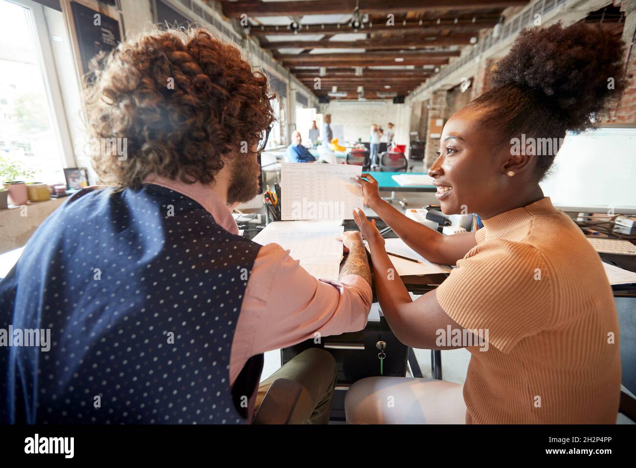 Young colleagues are reading a document while working in a pleasant atmosphere in the office ...
