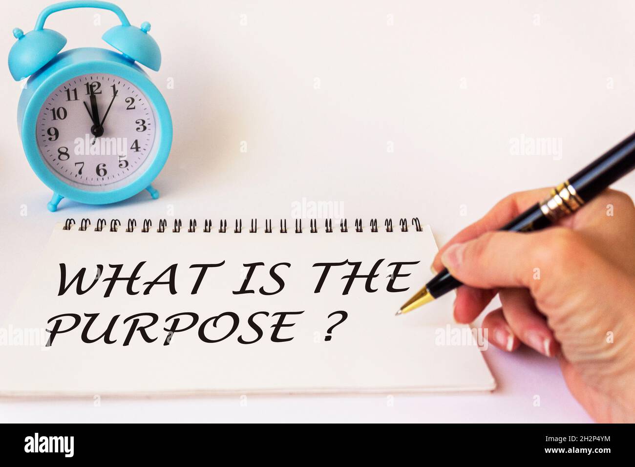 WHAT IS THE PURPOSE woman writes text in a notebook, close-up, top view ...