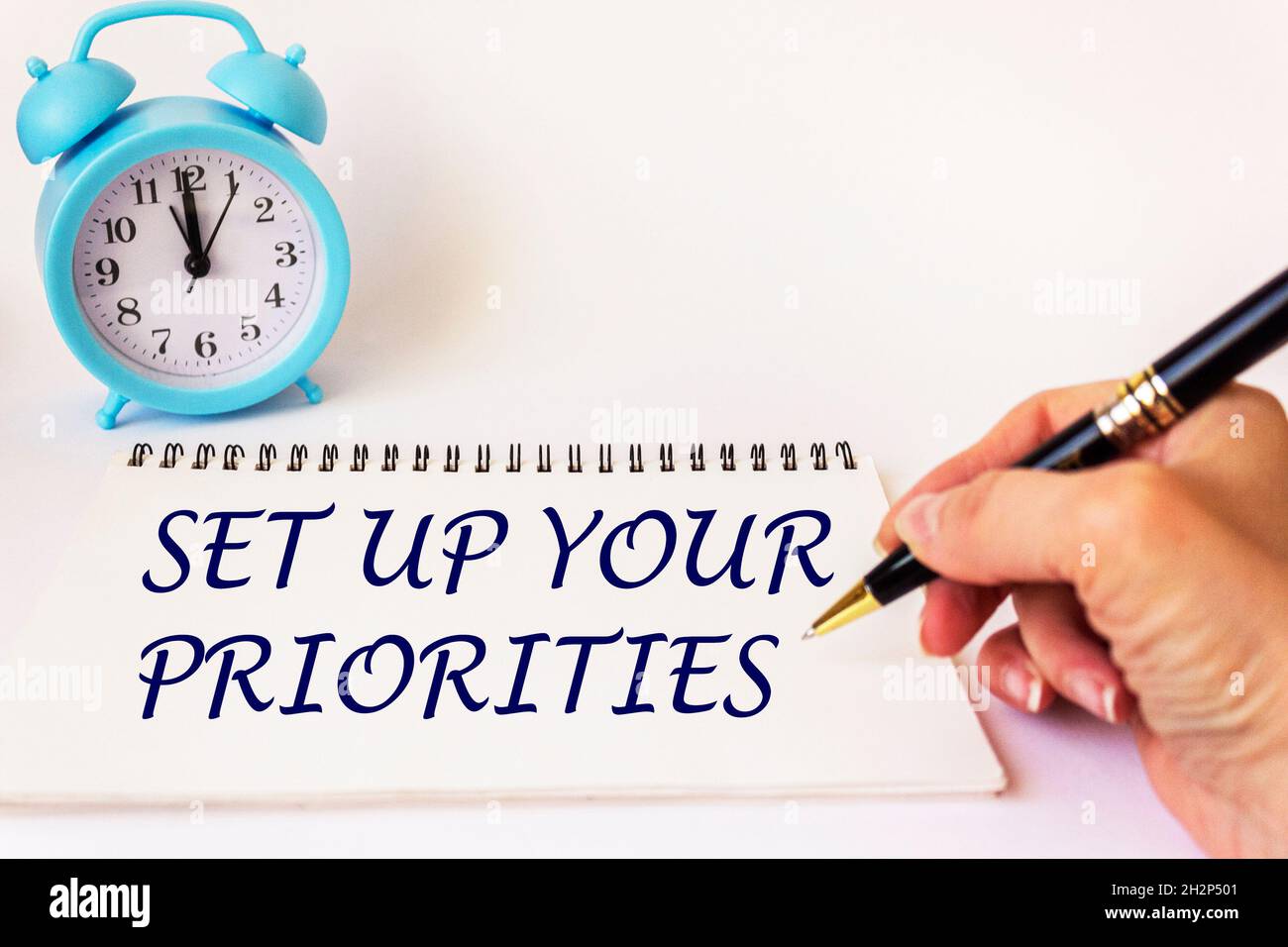 A woman's hand writes the text on a notepad Set your priorities. White ...
