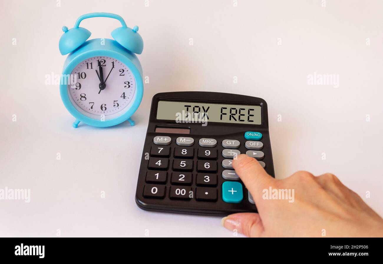 A woman's hand lies on a calculator with TAX FREE on the display on a ...