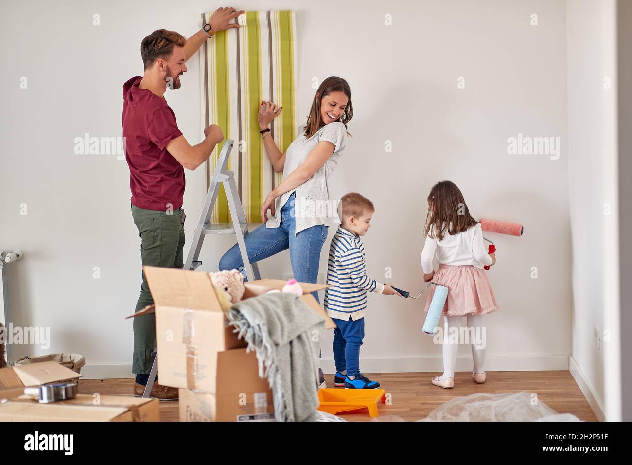 A young family in a cheerful atmosphere is painting and decorating ...
