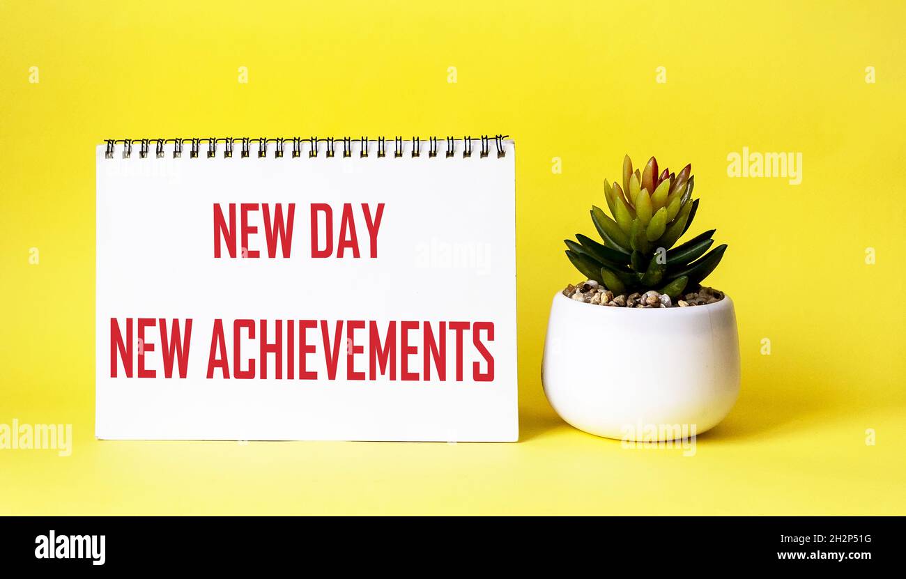 New Day New Achievements, the text is written on a notepad and a yellow ...
