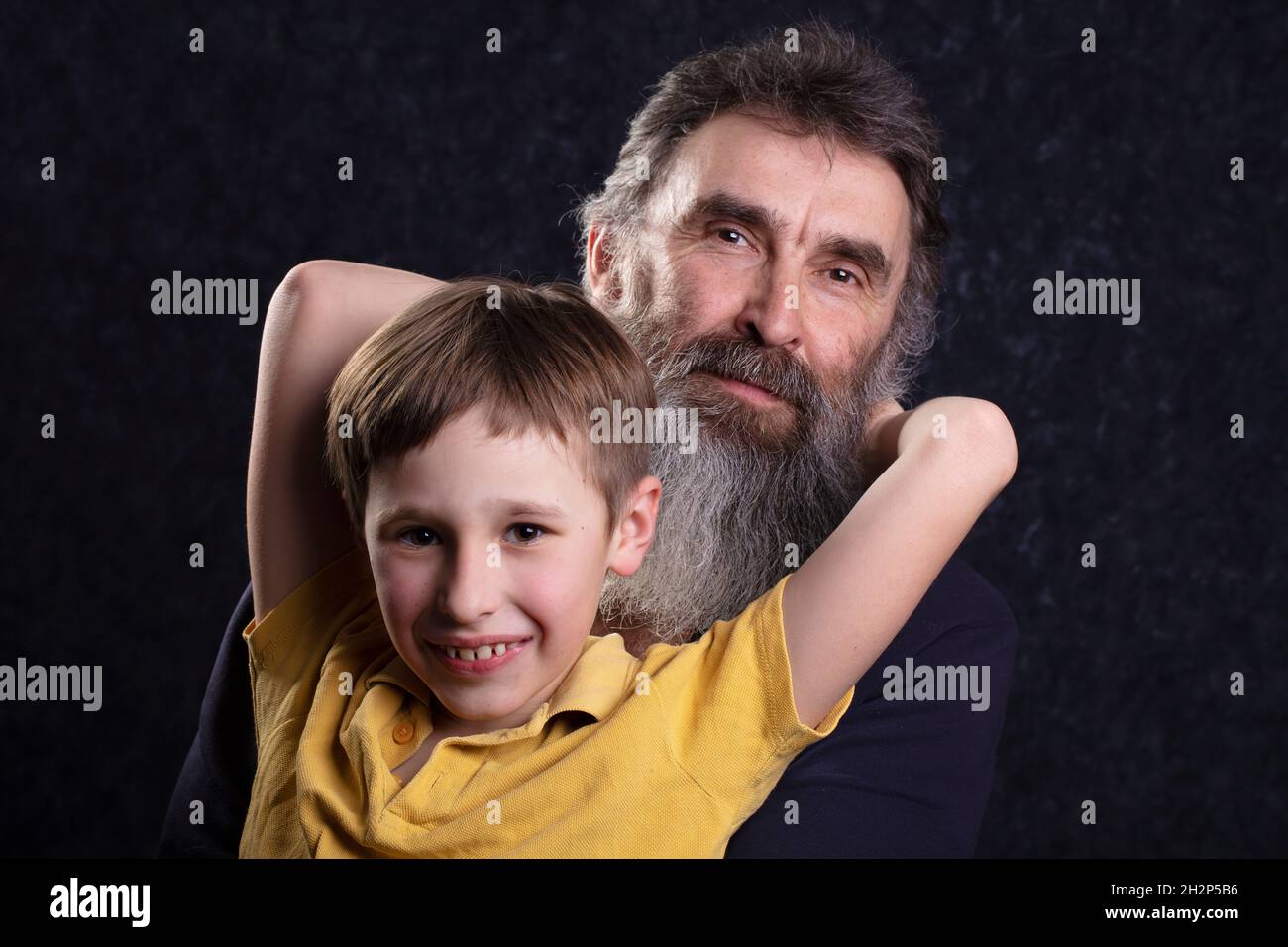 Portrait of a happy grandfather with a beard and grandson on a black ...