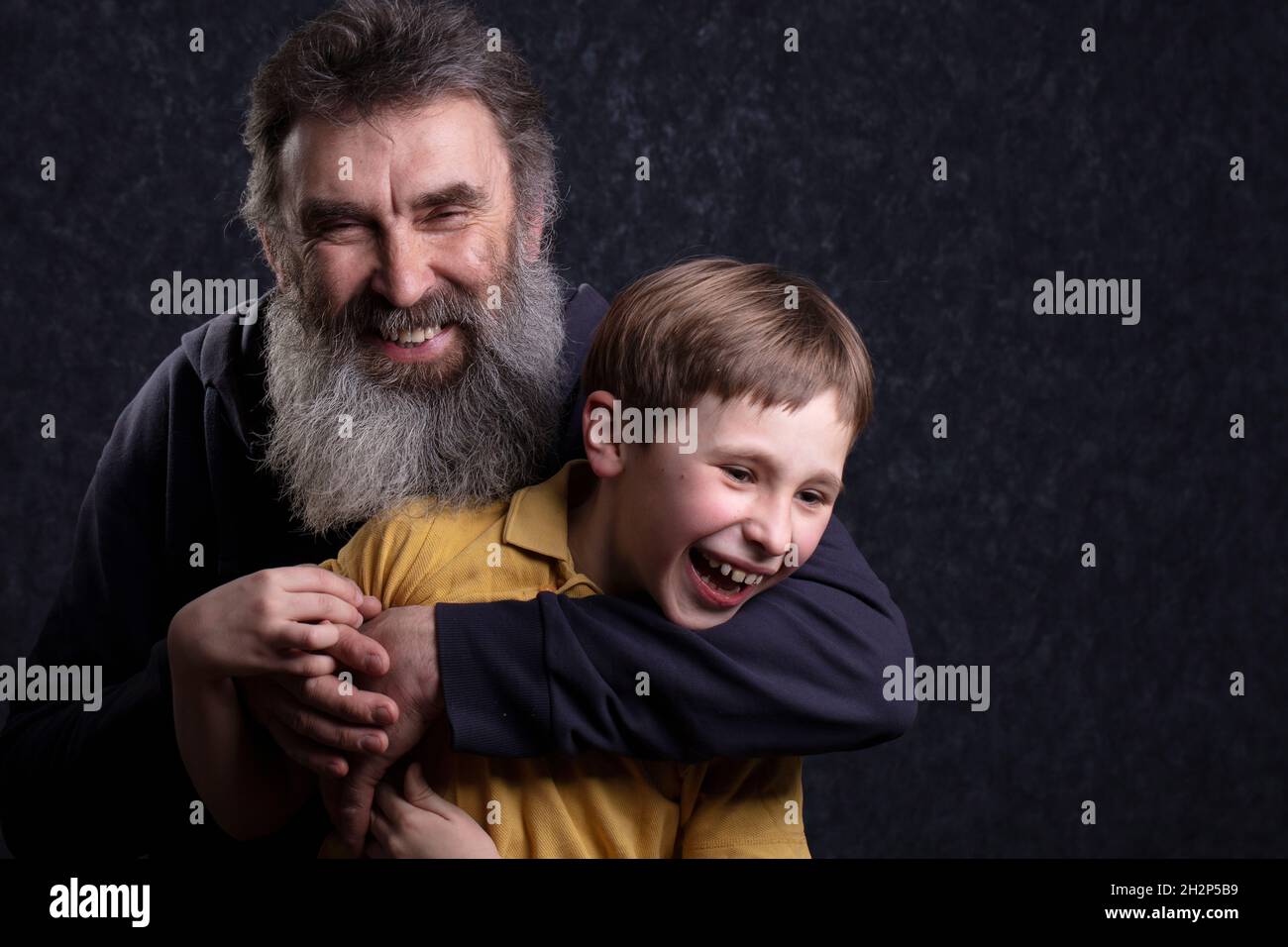 Portrait of a happy grandfather with a beard and grandson on a black ...