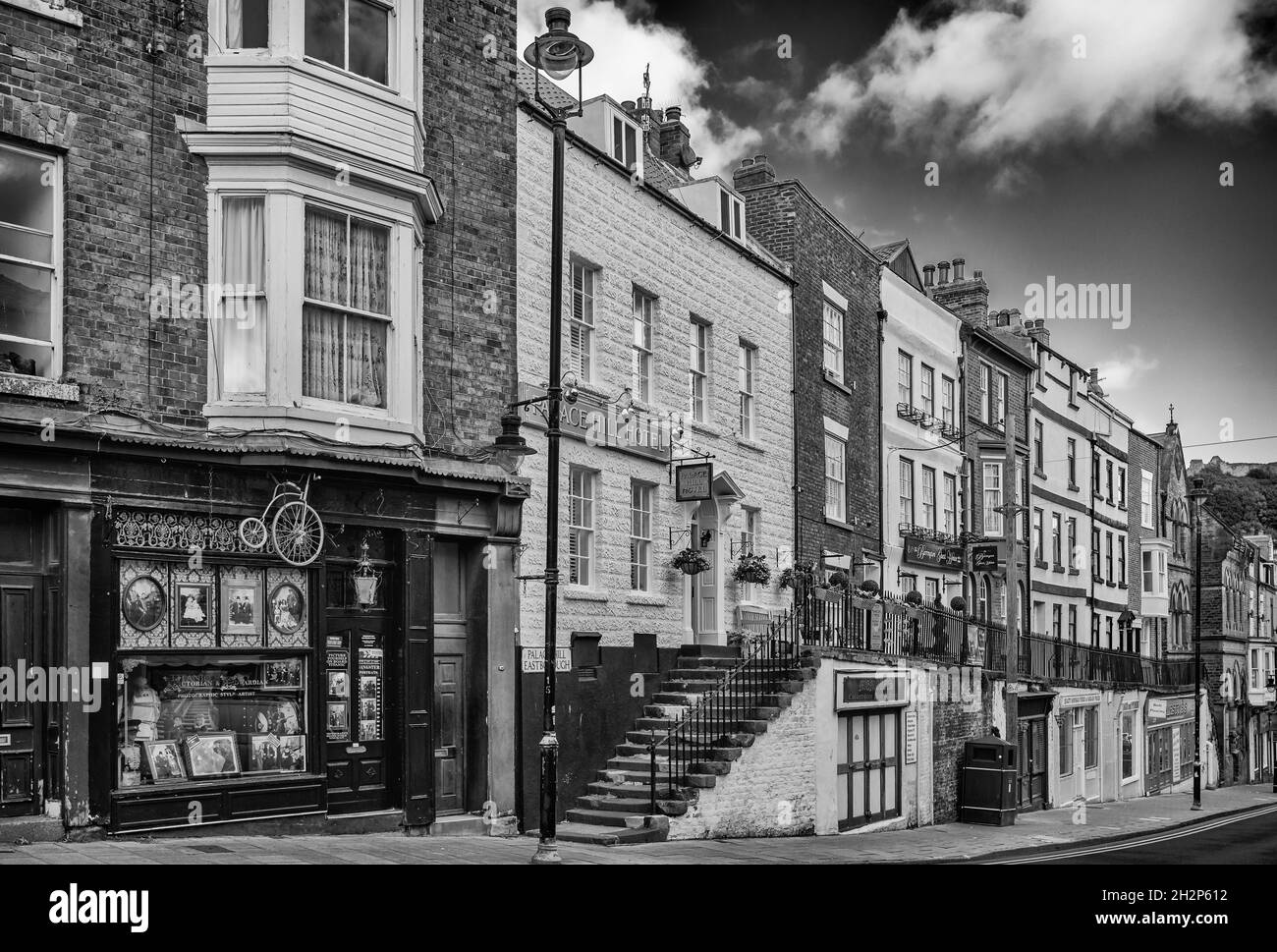 A sloping street with two levels. Steps lead up to houses and shops are ...
