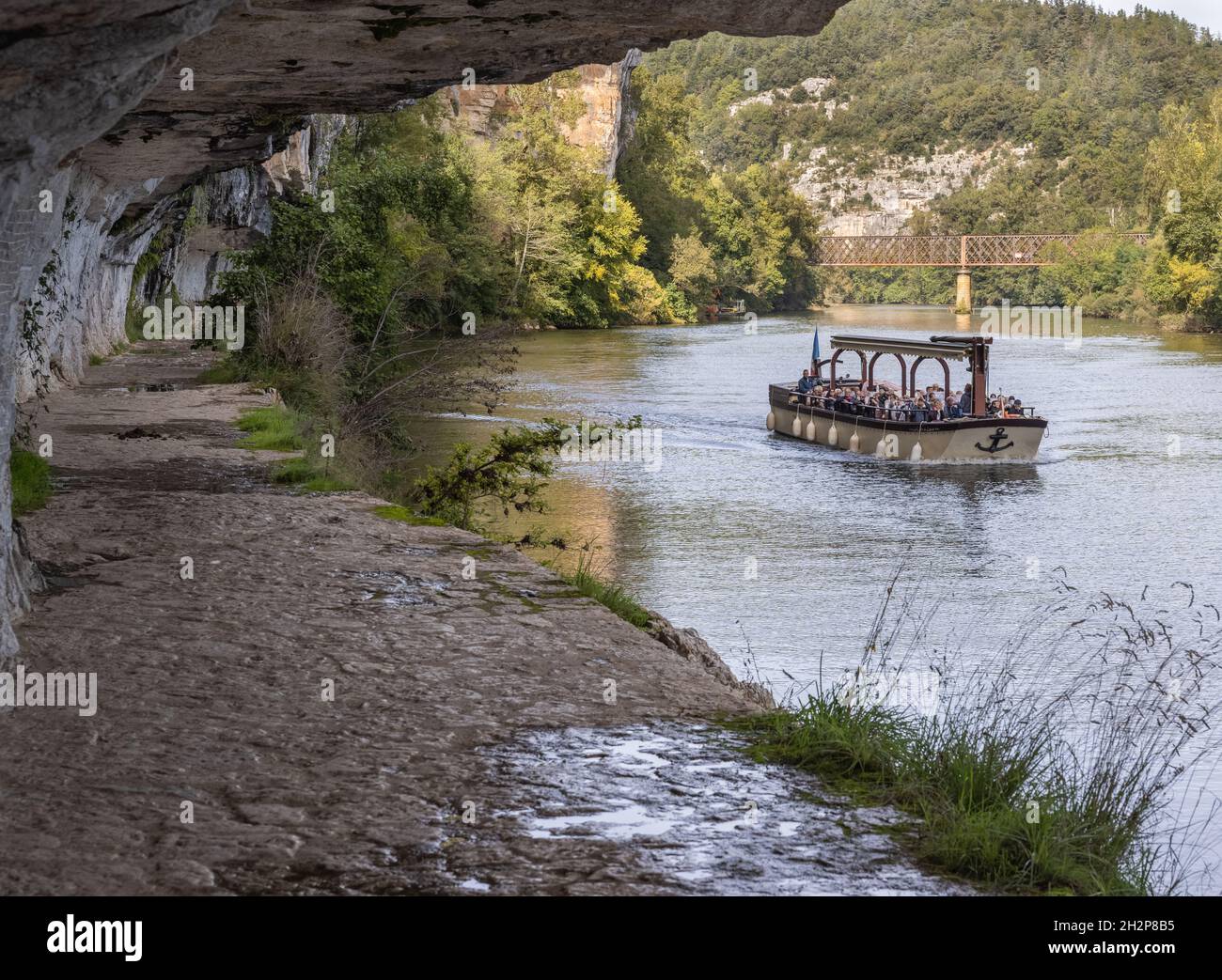 Tourist excursion boat on the Lot River and towpath carved into ...