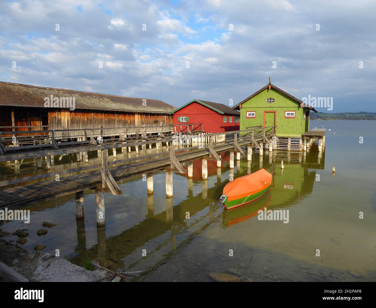 a long wooden pier leading to the colorful boat houses on lake Ammersee ...