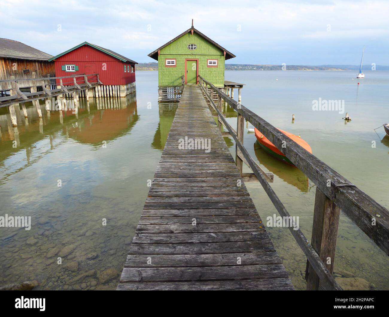 a long wooden pier leading to the colorful boat houses on lake Ammersee ...