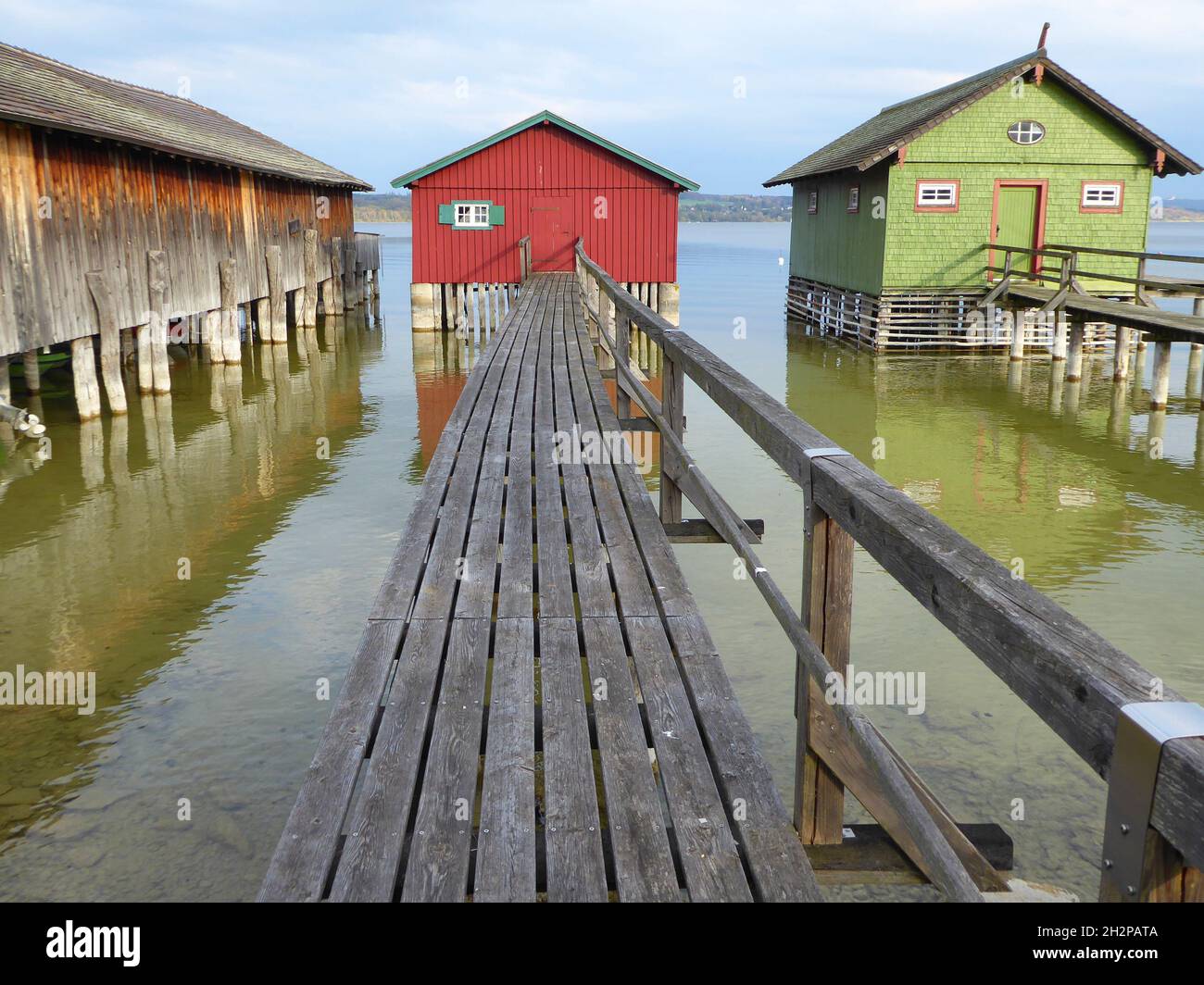a long wooden pier leading to the colorful boat houses on lake Ammersee ...