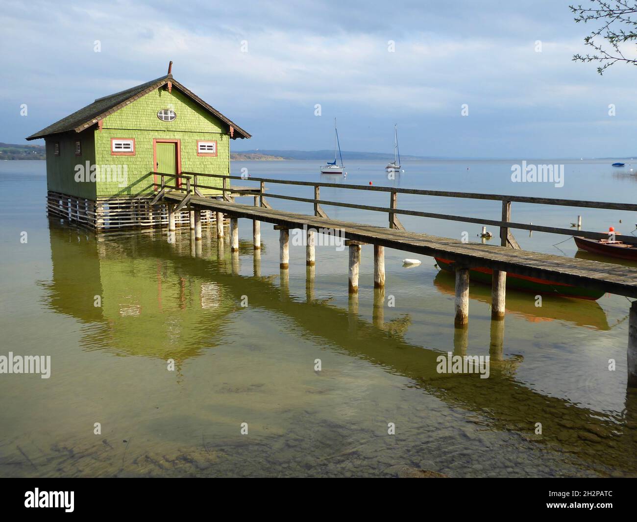 a long wooden pier leading to the colorful boat houses on lake Ammersee ...
