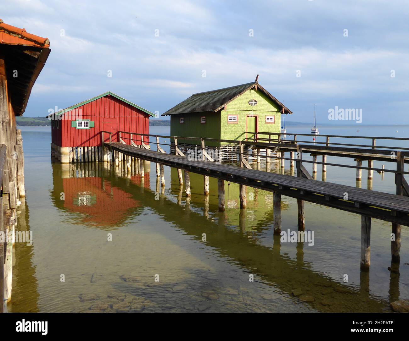 a long wooden pier leading to the colorful boat houses on lake Ammersee ...
