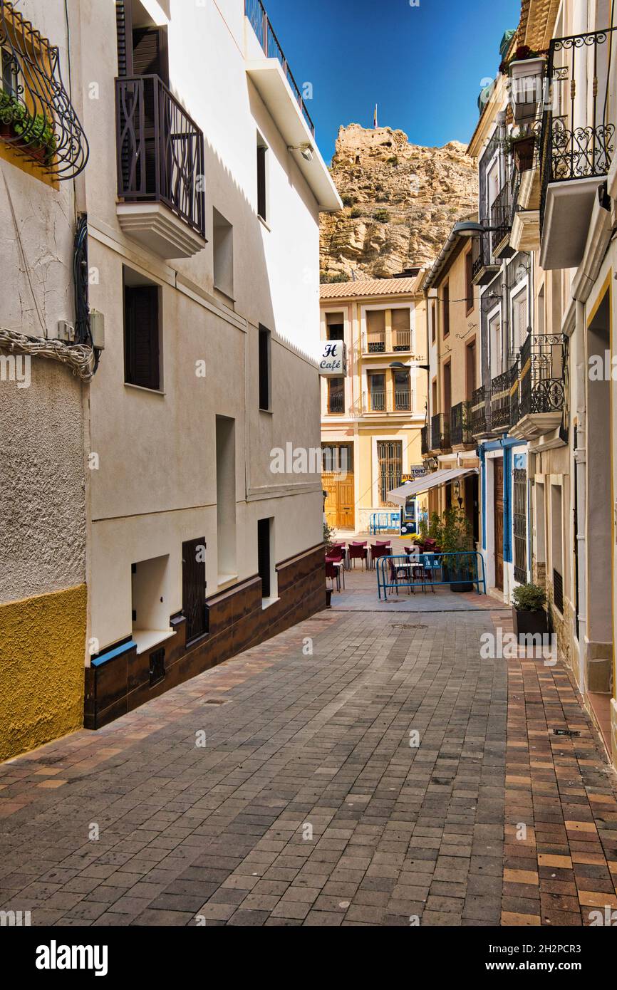 Narrow, historic street in Busot overlooking the hill with castle ruins ...
