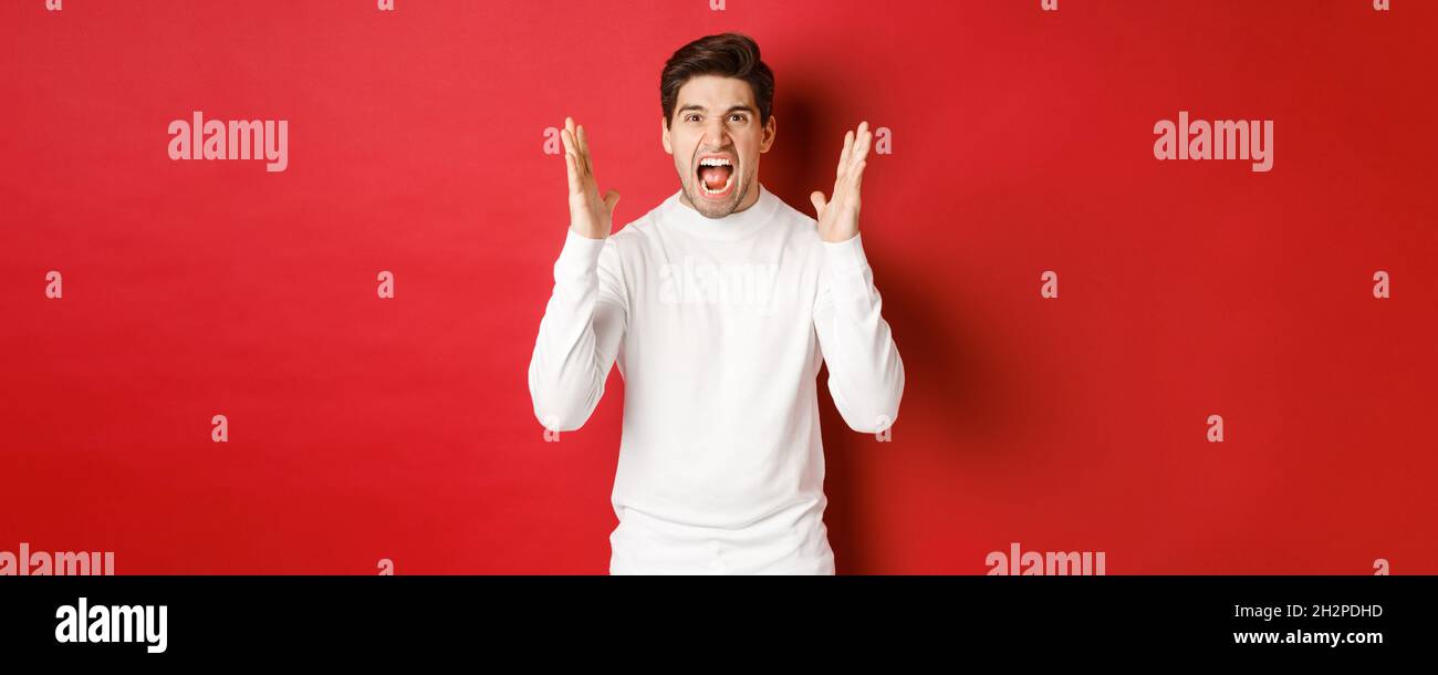 Image of frustrated and angry man in white sweater, shouting in rage ...