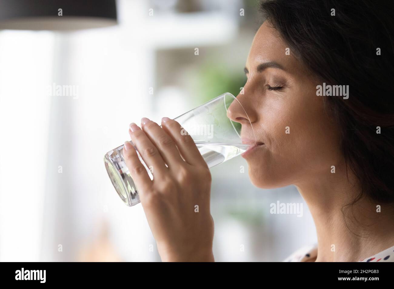 Peaceful woman satisfying thirst, drinking fresh pure clear cold water ...