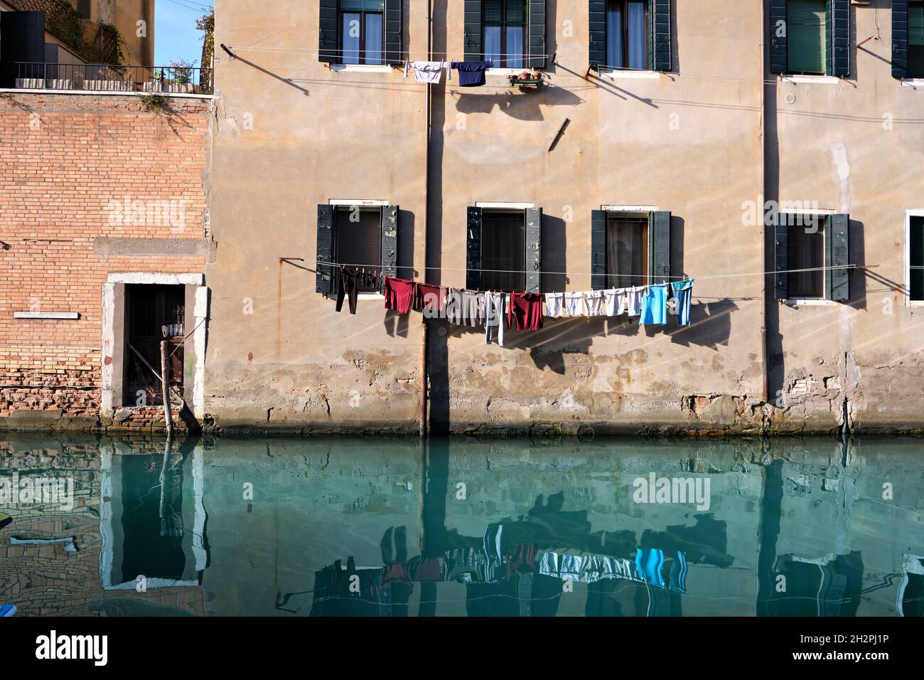 Washing lines along canal in Venice, Italy with reflection in water ...