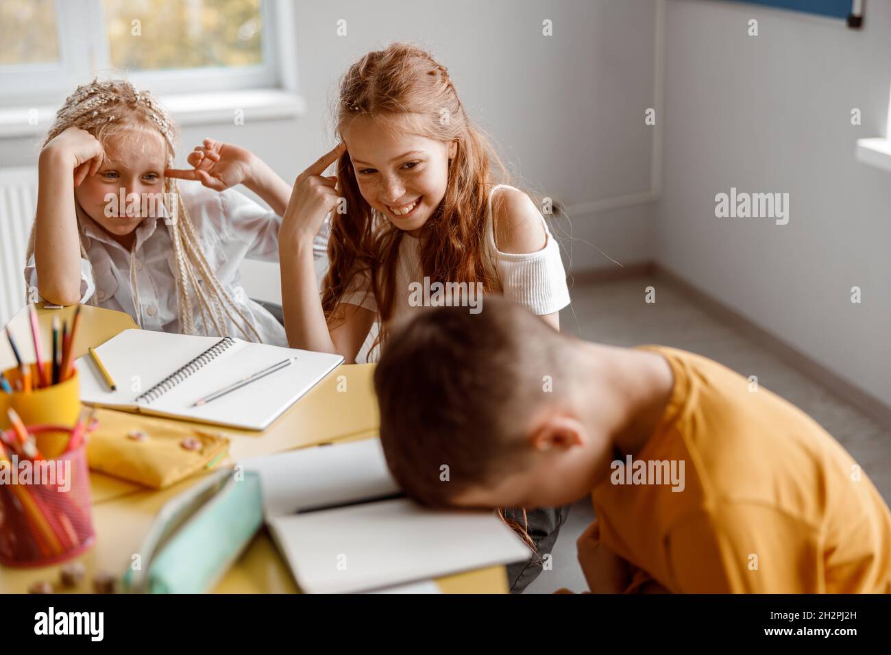 Happy girls joking at their classmate in class Stock Photo - Alamy