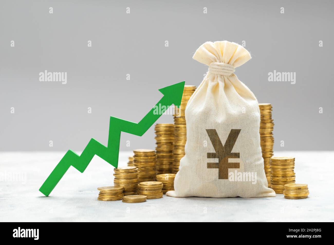 Green up arrow on the background of coins and a bag with the YUAN ...