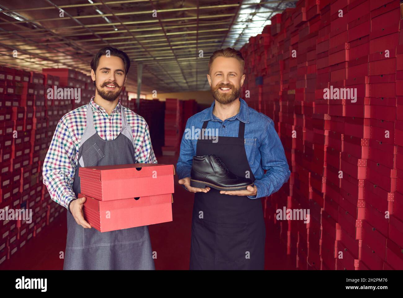 Happy shoe warehouse workers standing in aisle, holding boxes and ...