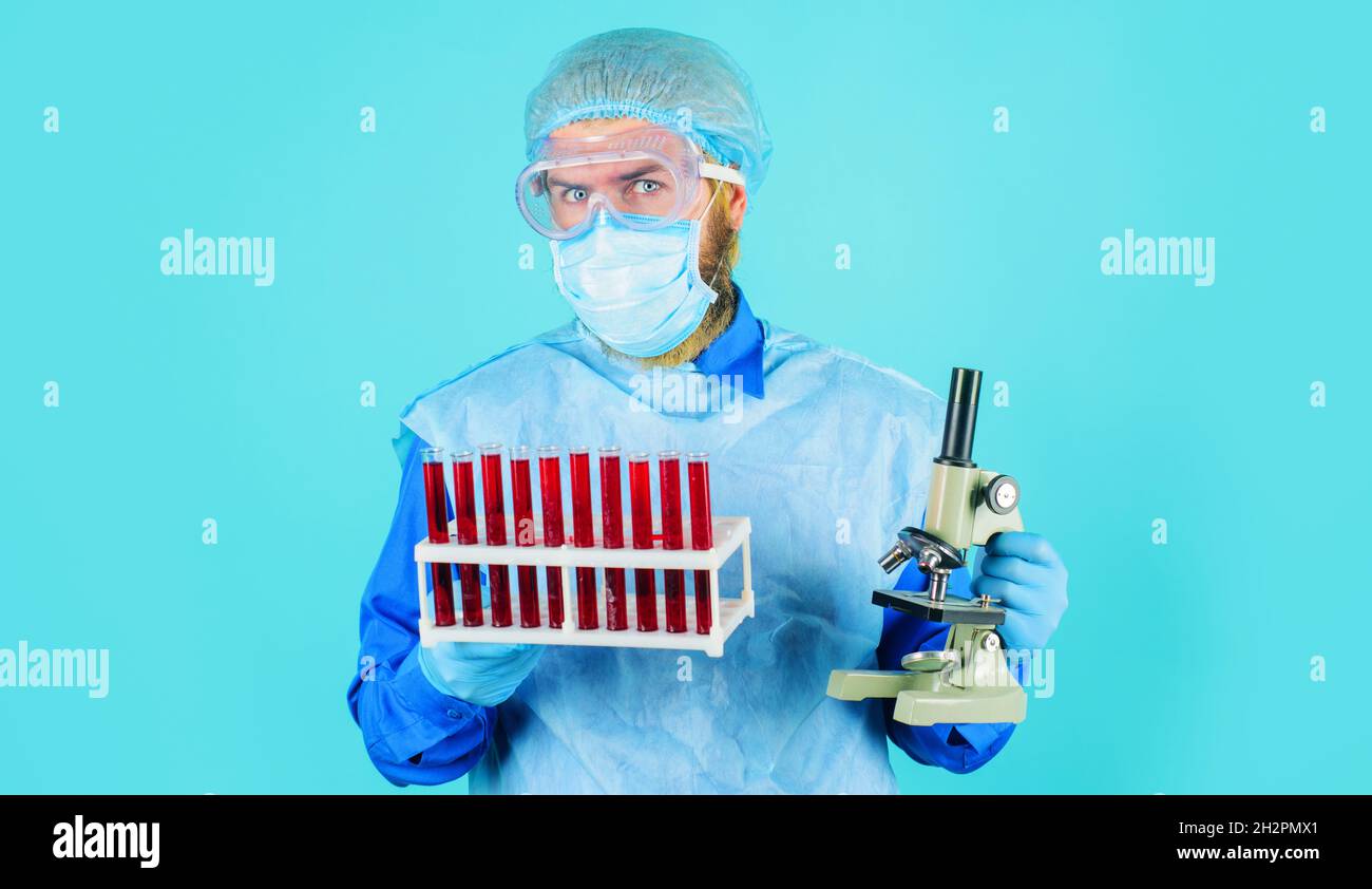 Laboratory work. Doctor in protective suit and mask with test tubes and ...