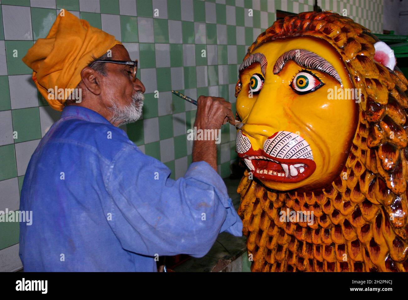 INDIA. BENARES. A MAN PAINTS THE TIGER DURGA IN THE TEMPLE OF SANKATA ...
