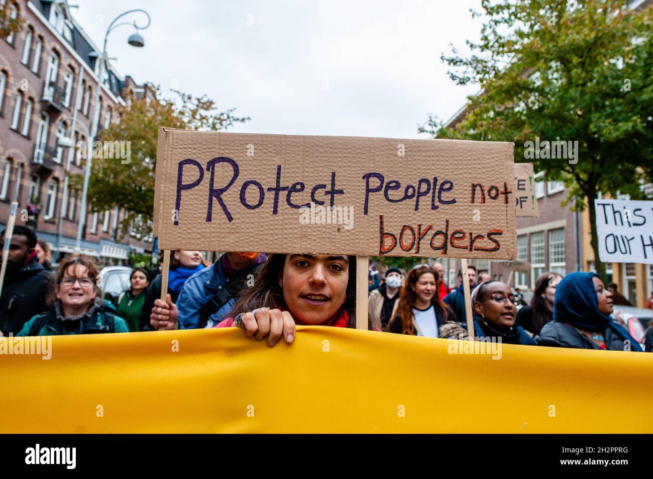 A woman is seen holding a placard asking for protection for ...