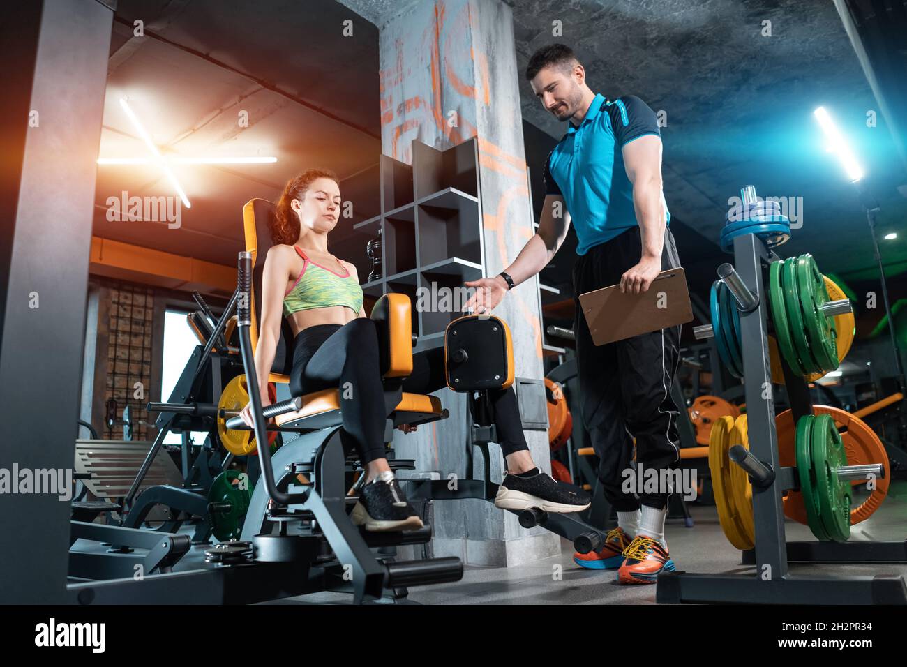 young woman exercising legs opening workout with personal trainer in ...