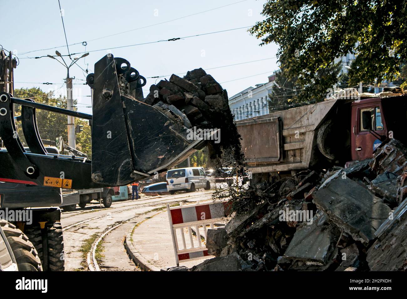 Excavator, grader and workers remove debris after dismantling a tram ...