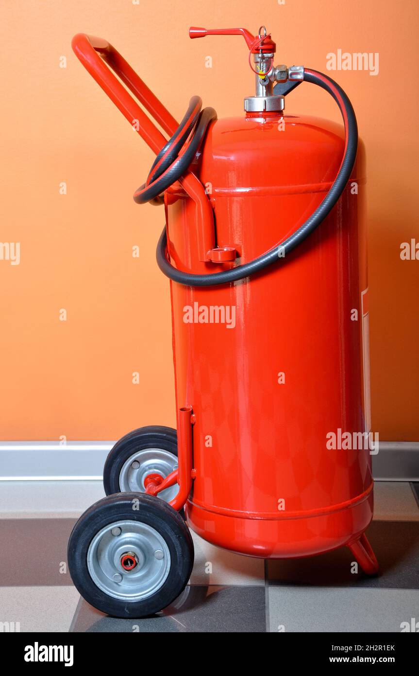 Red fire extinguisher, red fire tank, standing by the wall, ready to ...