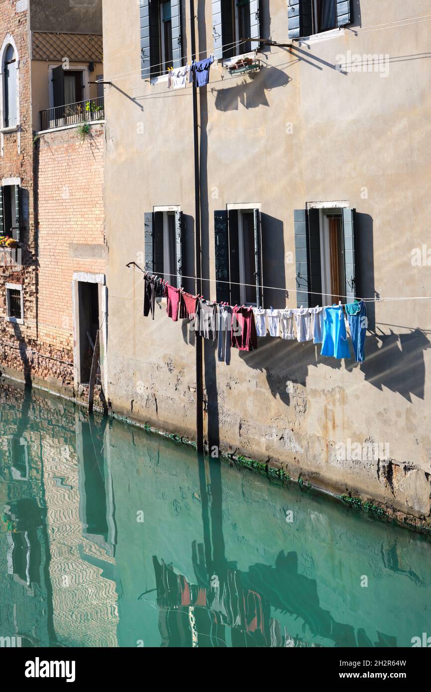 Washing lines along canal in Venice, Italy with reflection in water ...