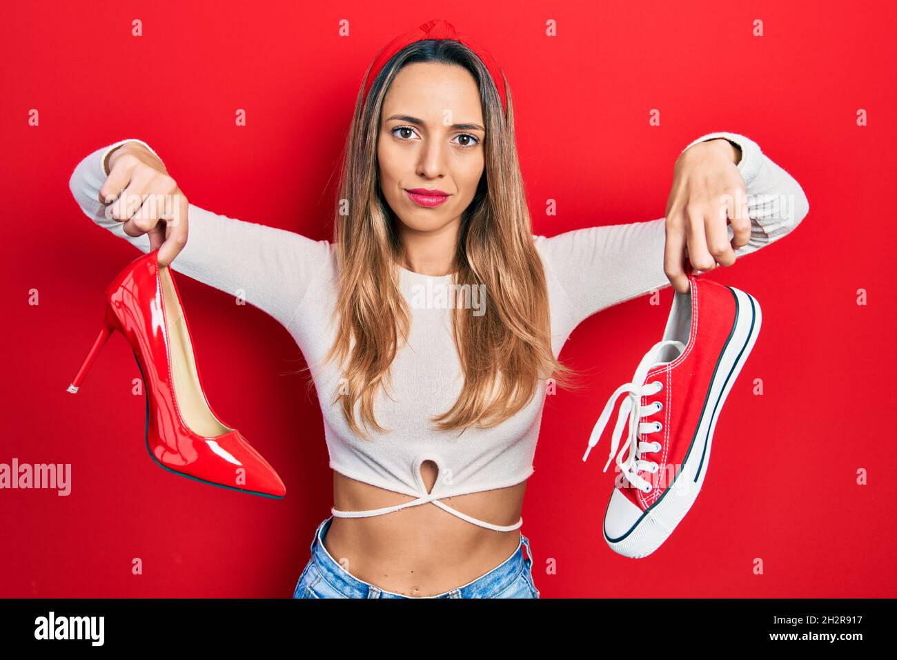 Beautiful hispanic woman choosing high heel shoes and sneakers relaxed ...