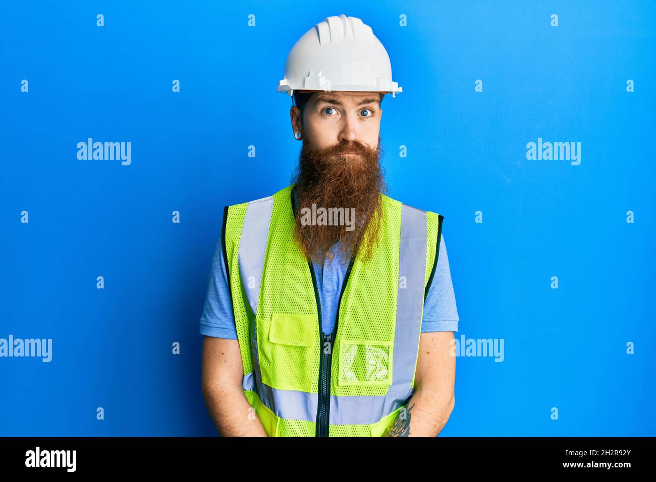 Redhead man with long beard wearing safety helmet and reflective jacket ...