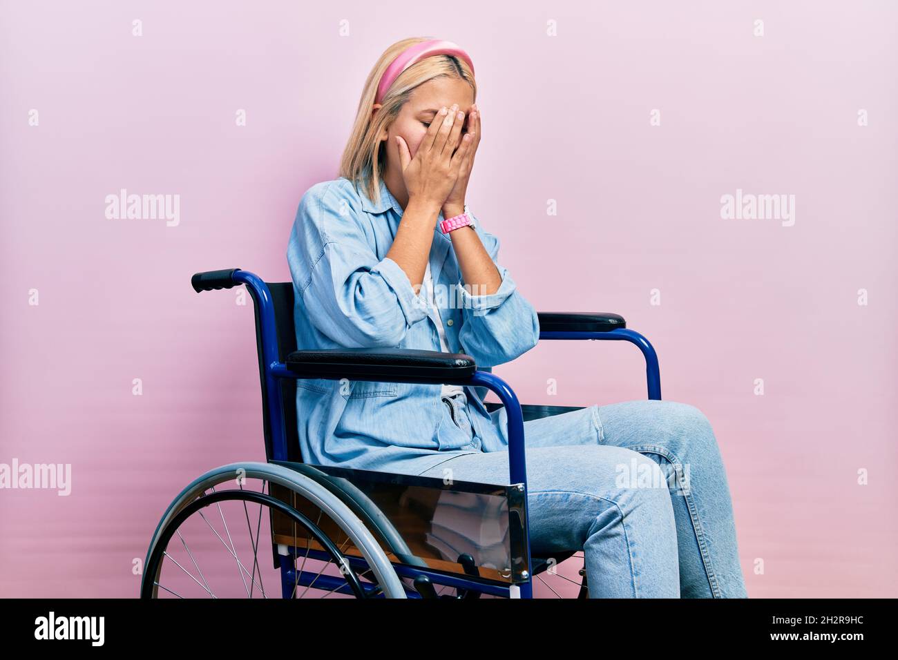 Beautiful blonde woman sitting on wheelchair with sad expression ...
