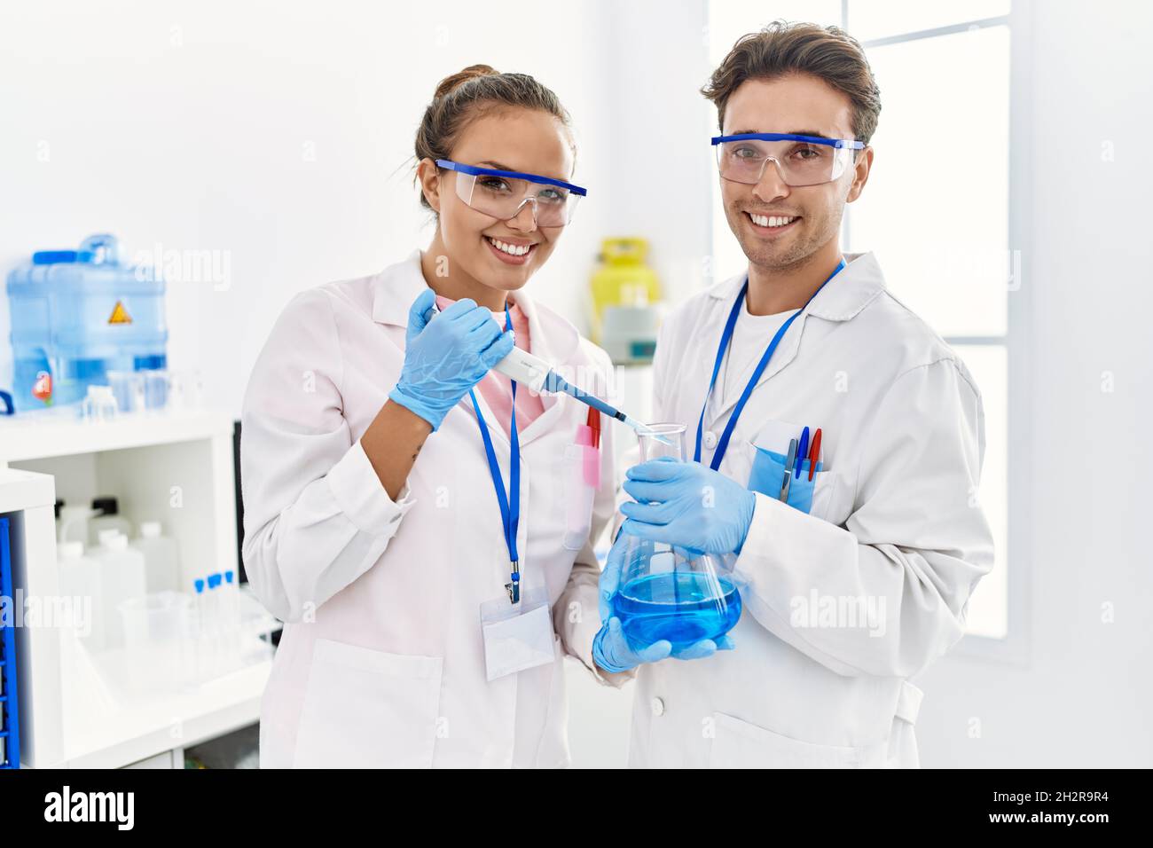 Man and woman wearing scientist uniform using pipette and test tube ...