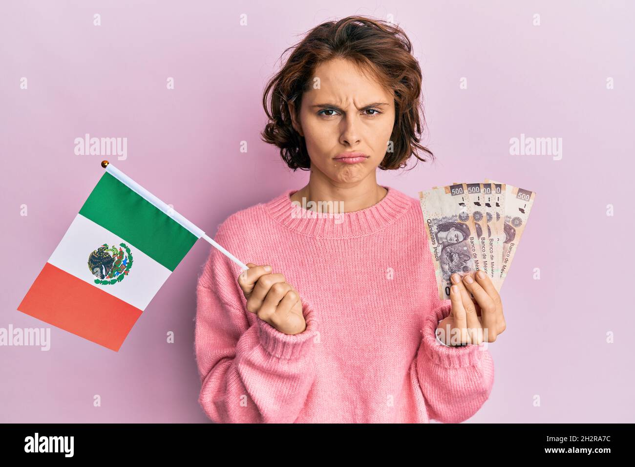 Young brunette woman holding mexico flag and mexican pesos banknotes ...