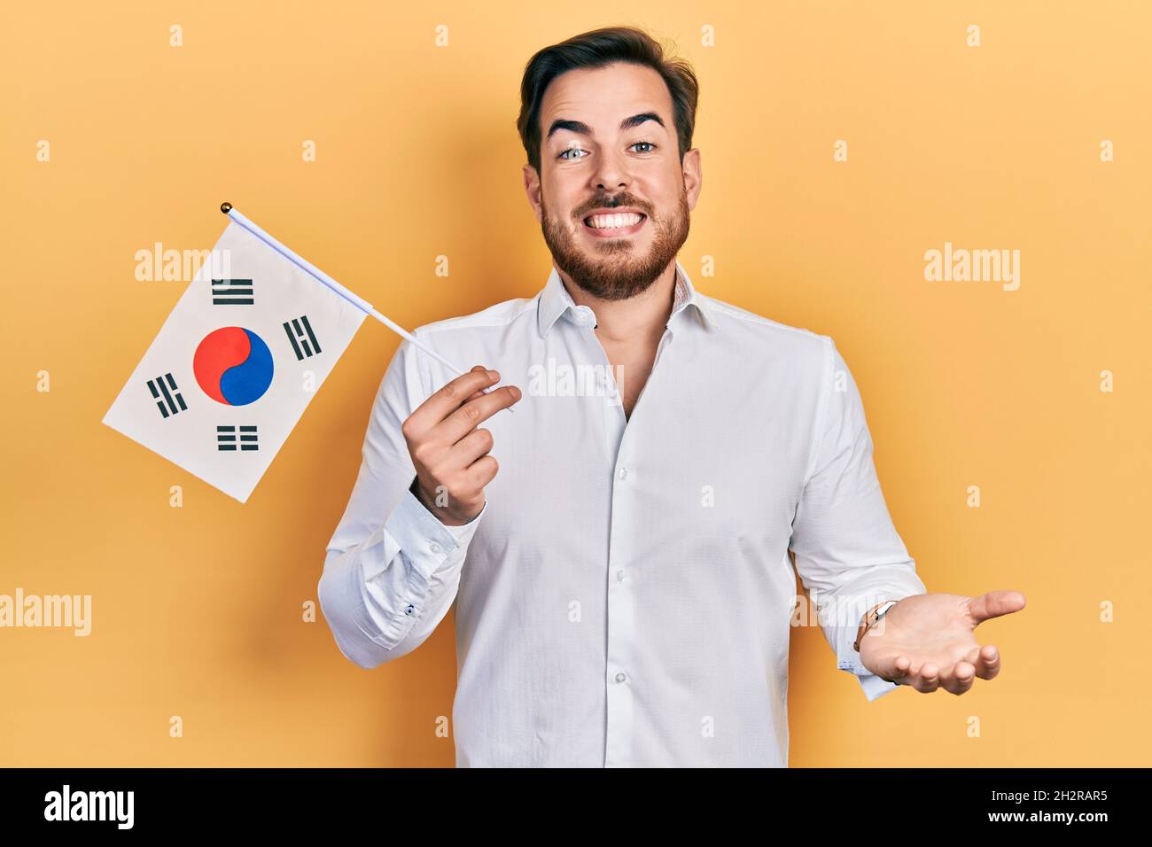 Handsome caucasian man with beard holding south korea flag celebrating ...