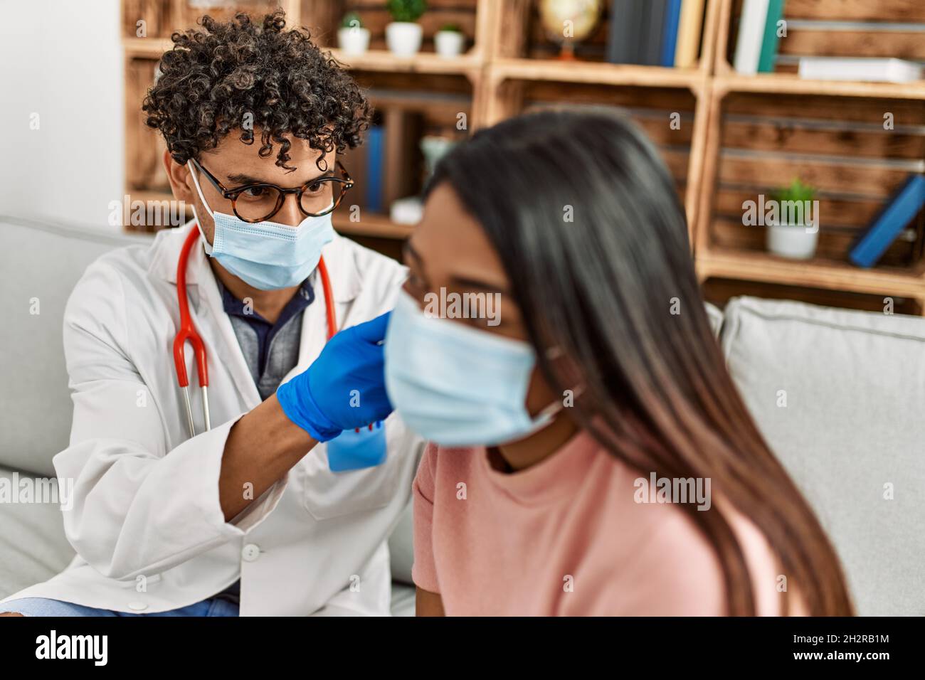Young latin doctor man auscultating the ear of woman using otoscope at ...