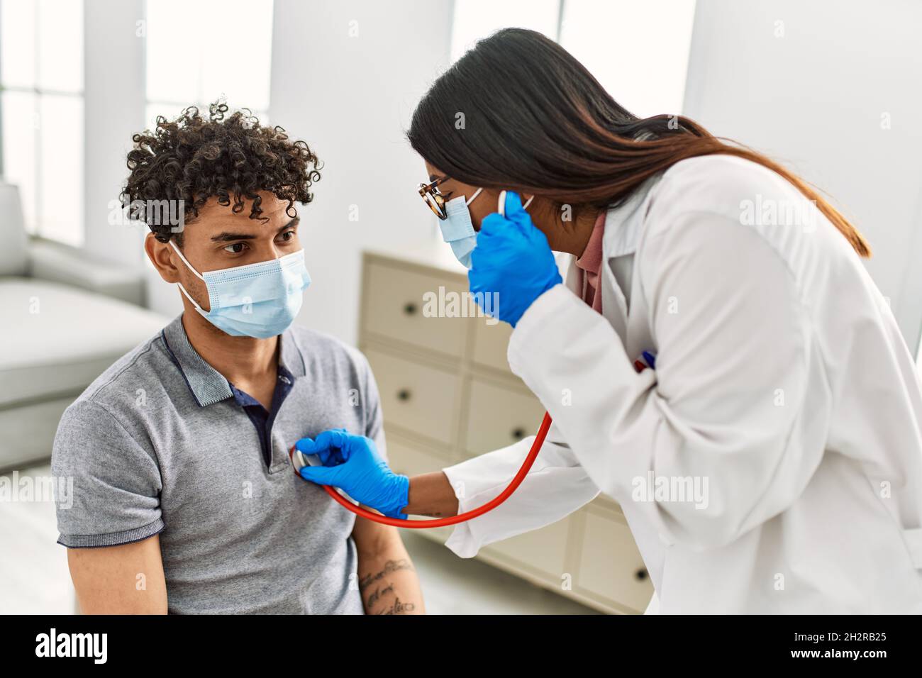Young latin doctor woman auscultate heart man using stethoscope at ...