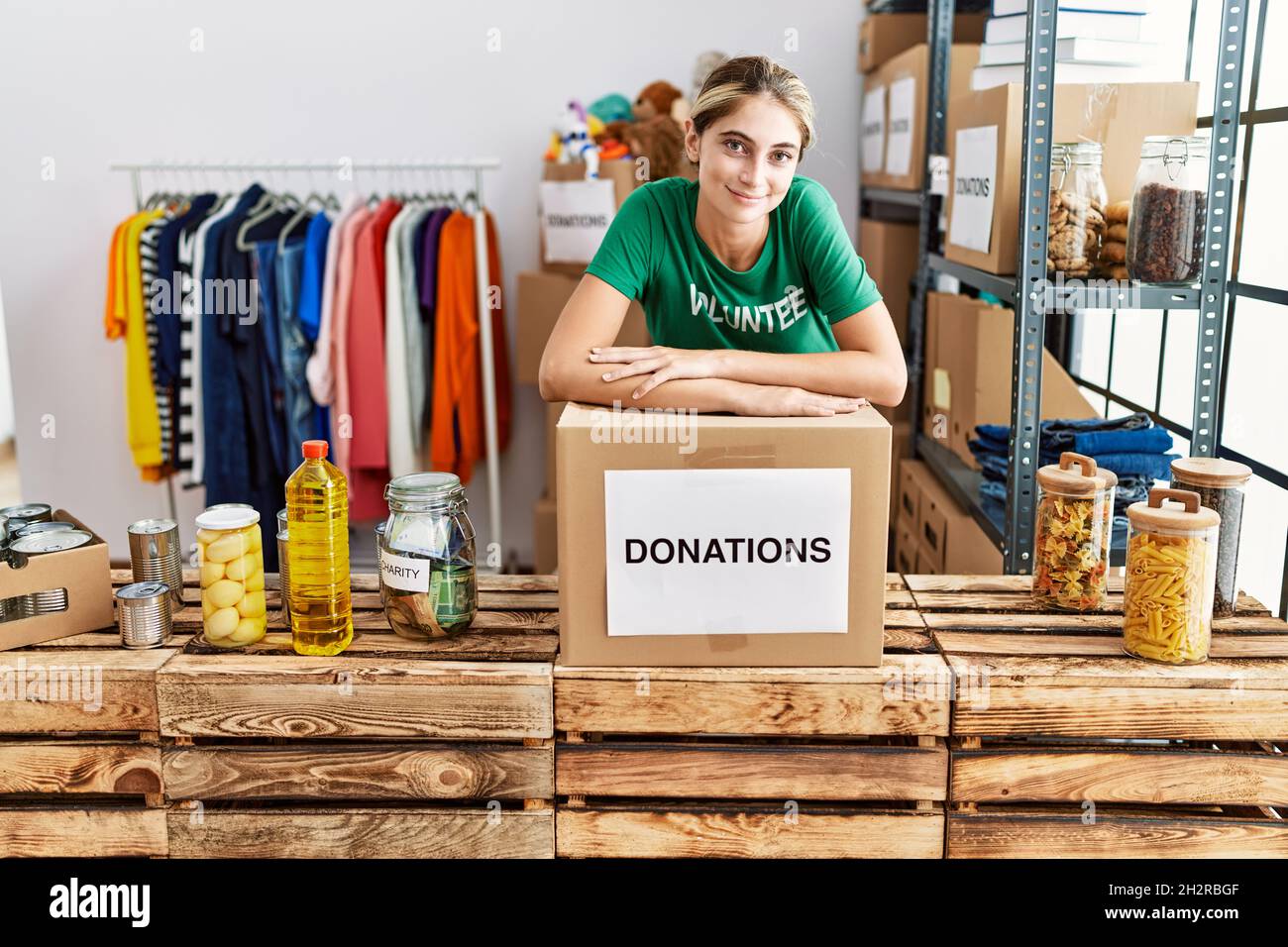 Young caucasian woman wearing volunteer uniform leaning on donations ... Young caucasian woman wearing volunteer uniform leaning on donations ...