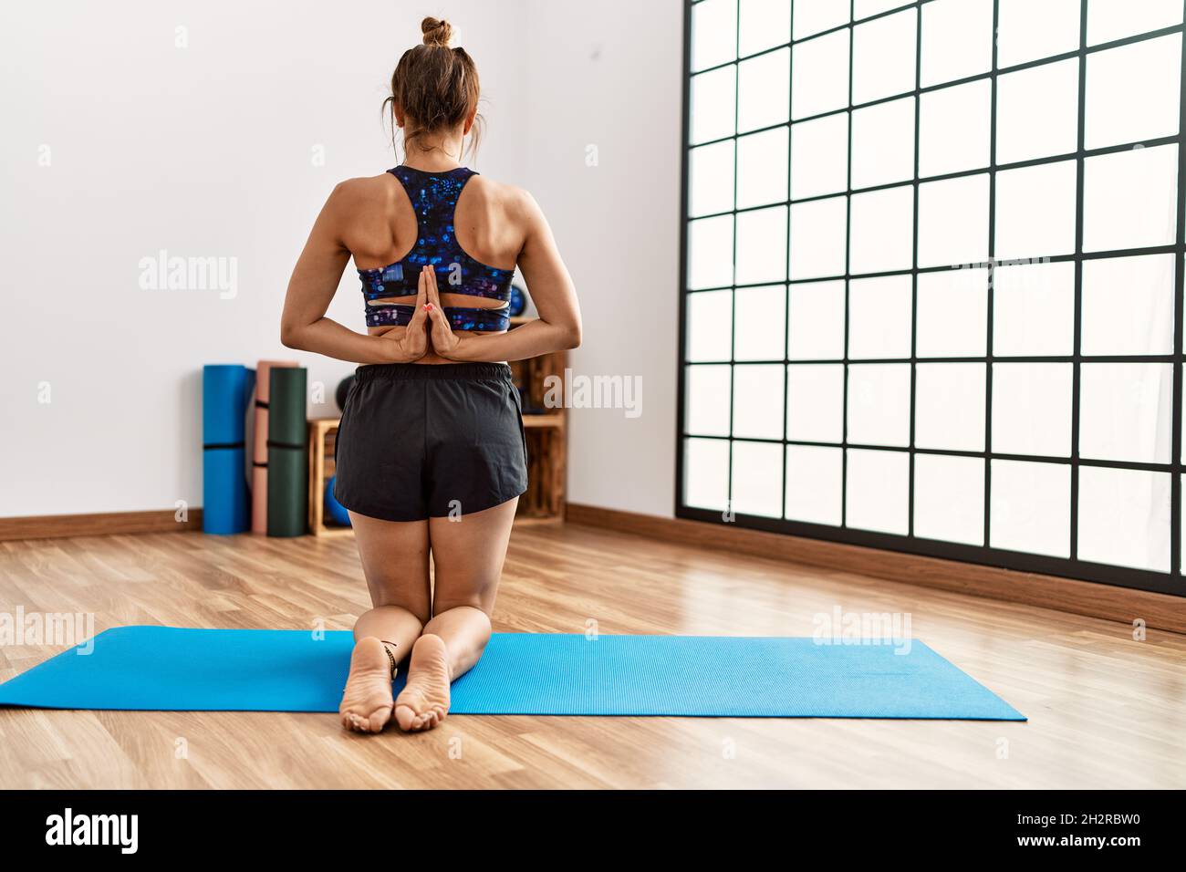 Young hispanic woman on back view training yoga at sport center Stock ...