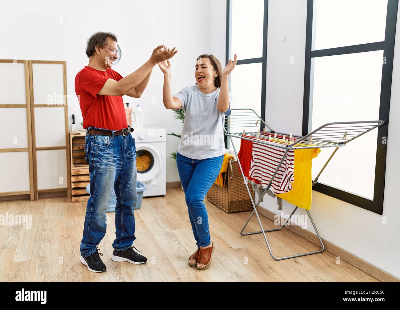 Middle age man and woman couple dancing waiting for washing machine at ...