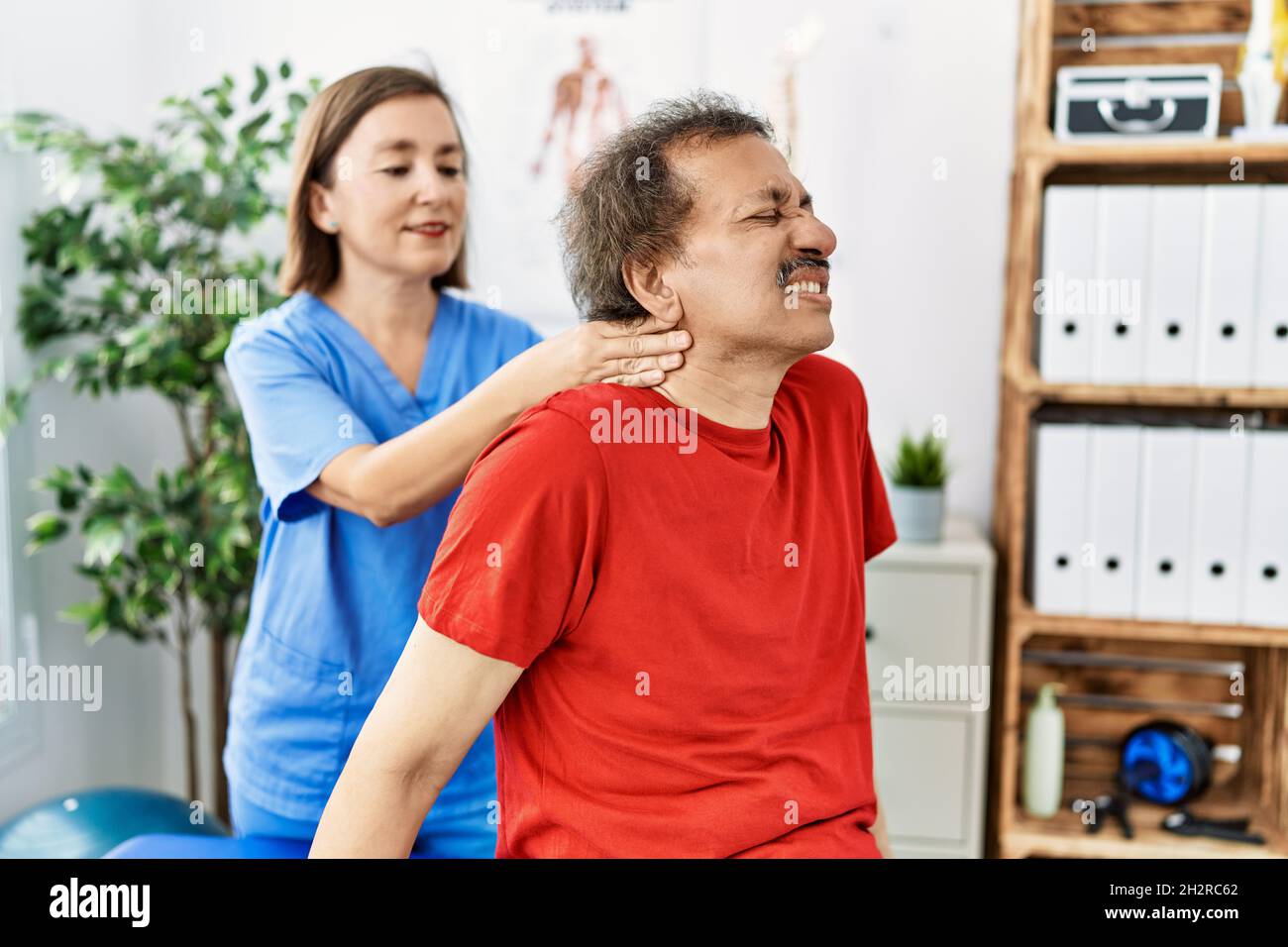 Middle age man and woman wearing physiotherapy uniform having rehab ...