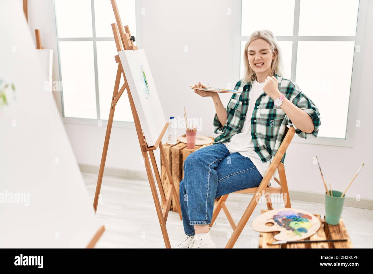 Young artist woman painting on canvas at art studio very happy and ...